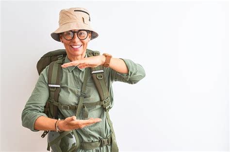 배낭 을 입고 중년 등산객 여성 배낭 수통 모자 안경 위에 고립 된 흰색 배경 몸짓으로 크고 큰 크기의 간판을 보여주는 손으로 기호를 측정 합니다 카메라를 바라보며 웃고