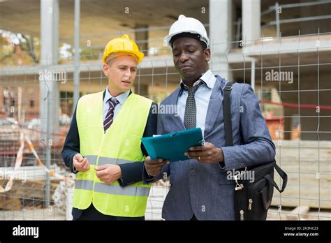 Architect And Engineer Discussing Documentation On Construction Site