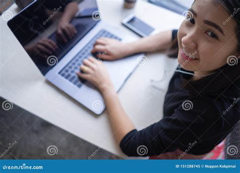 Happy Asian Girl Listening Music On Mobile Phone Working On Laptop