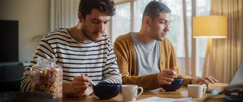 Two Handsome Friends Are Eating Colorful Breakfast Cereal In Cozy