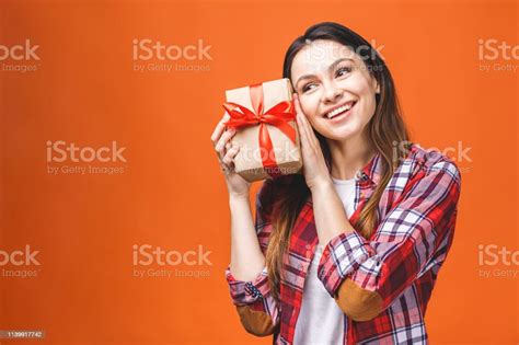 웃는 젊은 아름 다운 여자의 스튜디오 초상화는 빨간 선물 상자를 보유 하 고 있습니다 오렌지 배경에 고립 매우 기쁜에 대한 스톡 사진 및 기타 이미지 Istock