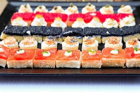 생선 빨간색과 검은 색 캐비어를 곁들인 많은 작은 다채로운 샌드위치 해산물을 곁들인 핑거 푸드 초밥은 결혼식을위한 작은 간식을