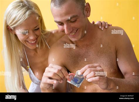 Couple Practicing Safe Sex By Using A Condom Barrier Device Before Having Sexual Intercourse