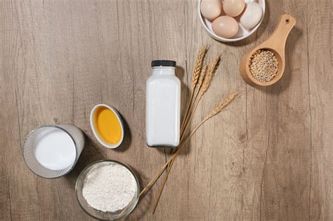 나무 테이블 부엌 배경에 대해 라벨이 붙지 않은 우유 병 유리 그릇에 밀가루 작은 그릇에 기름 밀과 계란에 다양한 베이킹 재료에 대하여 요리 광고를 위한 평면도 사진