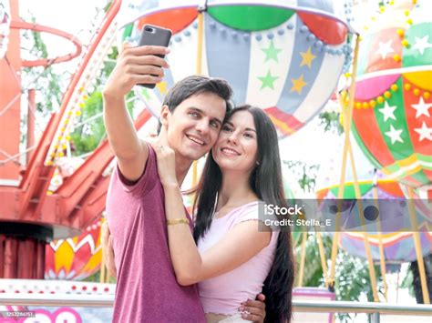 주말에 테마 파크에서 함께 시간을 보내는 십대 부부 아름다운 젊은 연인이 놀고 놀이 공원에서 즐거운 시간을 보내고 셀카를 찍고