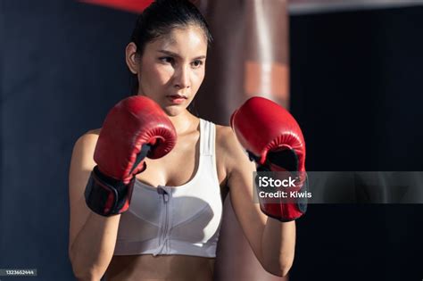 아시아 보디 아름다운 여자 선수는 권투 장갑을 착용 펀칭 가방 이나 복싱 샌드백을 타격 하 여 운동 운동을 하 고 젊은 스포츠