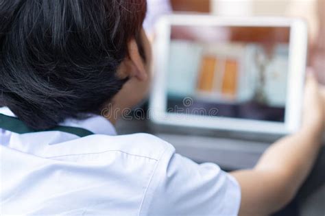 Back View Of Asian Boy Using Digital Tablet While Sitting On Desk At Home Stock Image Image Of