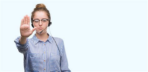 젊은 금발 콜 센터 운영자 여자 오픈 손으로 하 고 심각 하 고 자신감 표현 방어 제스처와 정지 신호 경계 표지에 대한 스톡