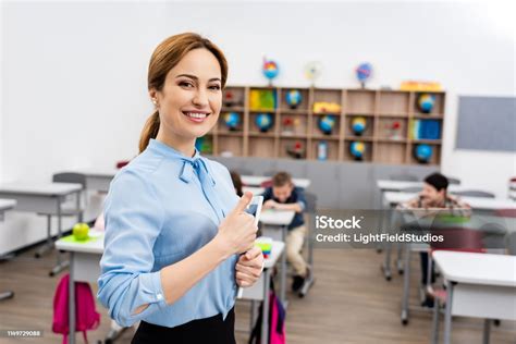 파란색 블라우스에서 학생 들의 앞에 서 서 엄지 손가락을 보여주는 웃는 교사 3 명에 대한 스톡 사진 및 기타 이미지 3 명 고등학교 이하 공부 Istock