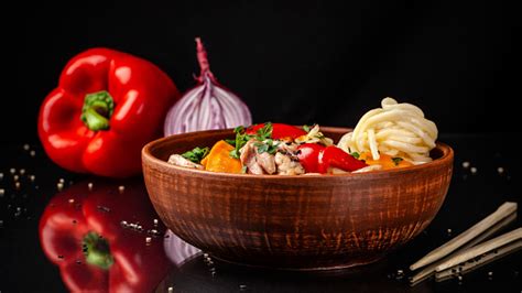 닭고기와 야채 불가 리아 어 후추 붉은 양파 검은 참 깨와 일본 중국 우동 국수 검은색에 빨간 점토의 만든 도자기 그릇에 요리