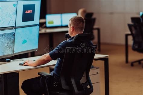 Group Of Security Data Center Operators Working In A Cctv Monitoring Room Looking On Multiple