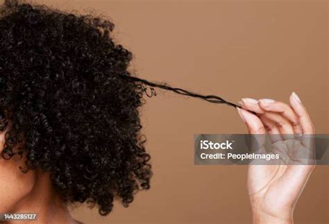 헤어 케어 뷰티 스튜디오에서 갈색 배경에 곱슬머리를 한 흑인 여성 손 미용실 웰빙 및 성장 자연스럽고 건강한 모발을 위한 컬 마케팅 헤어 트리트먼트 제품을 들고 있는 소녀