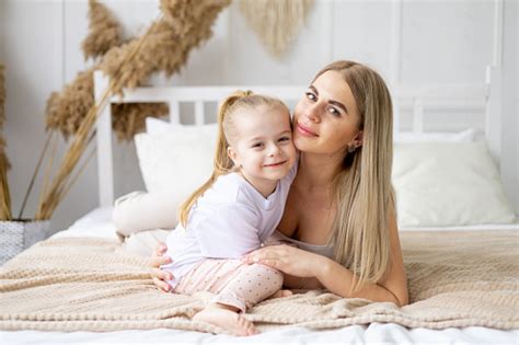 엄마와 딸은 침대에서 집에서 놀고 포옹하고 키스하고 라이프 스타일 젊은 엄마와 아이의 부드러운 관계 행복한 가족과 모성 2 3