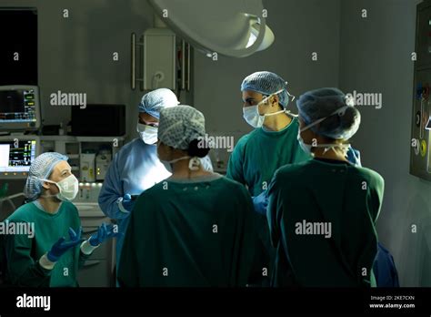 Diverse Group Of Male And Female Surgeons In Discussion In Operating Theatre Before Operation