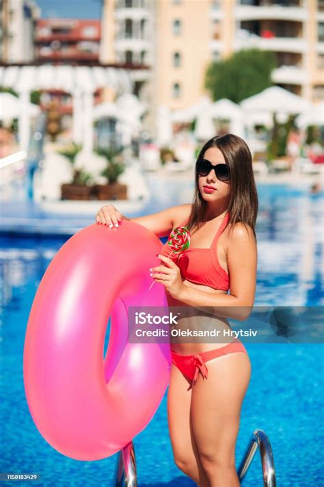 수영장에서 일광욕을 하는 분홍색 수영복을 입은 아름다운 소녀 소녀 보유 사탕과 고무 반지 가냘픈에 대한 스톡 사진 및 기타 이미지 가냘픈 날씨 낮 Istock
