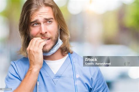 강조 하 고 손톱을 물어 뜯고 입에 손을 긴장을 찾고 격리 된 배경 위에 긴 머리를 가진 젊은 잘생긴 의사 남자 불안 문제입니다 감정에 대한 스톡 사진 및 기타 이미지