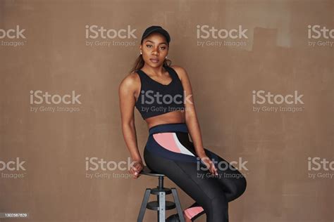 갈색 배경이있는 스튜디오에서 의자에 앉아있는 젊은 아름다운 아프로 미국 여성 20 24세에 대한 스톡 사진 및 기타 이미지 20 24세 갈색 갈색 머리 Istock