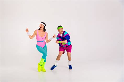 복고풍 스포츠웨어를 입은 활기찬 커플이 흰색 배경에 펑키한 댄스 동작을 선보이며 즐겁고 활동적인 라이프스타일을 보여줍니다 2명에