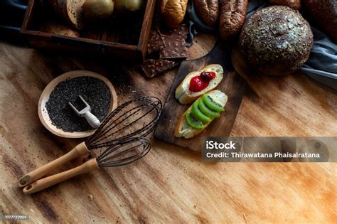 조식 및 구운된 빵 개념입니다 신선한 향기로운 빵 그리고 나무 테이블에 알입니다 신선한 빵과 커피 나무 검은 배경에 밀 키 위 고 초콜릿입니다 접시에 참 깨 씨앗입니다