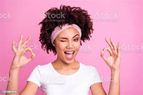 갈색 머리 낙관적 인 레이디 쇼 Okey 사인 깜박이 파스텔 핑크 배경에 고립 된 흰색 티셔츠 헤어 밴드를 착용하는 초상화 T
