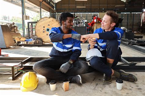 안전 작업복을 입은 행복한 팀워크 기술자 엔지니어는 주먹 부딪히는 성공을 축하합니다 산업 제조 공장에서 샌드위치와 커피와 함께 식사하는 동안 완료된 거래 약속 25 29세에