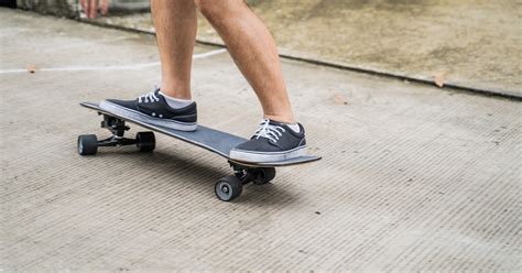 그의 집 앞 거리에서 활동적인 아시아 힙 스터 남자 타기 서핑 스케이트 보드의 다리를 닫습니다 익스트림 스포츠 맨 스케이팅 선수는 건강 관리와 웰빙을 위해 자유 시간