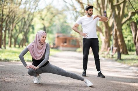 Premium Photo Woman In Hijab Warming Up While Man Using Smart Watch