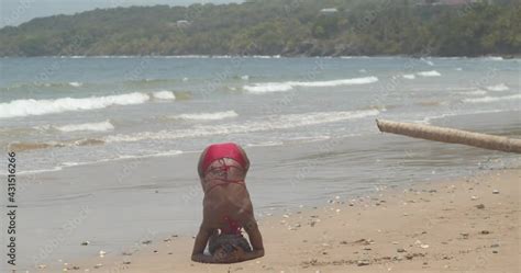 Contortion Flexible Girl In A Bikini Doing A Hand Stand With Waves Of The Ocean Crashing In The