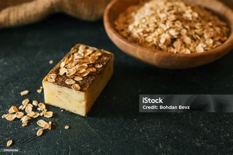 귀리 플레이크가 담긴 나무 숟가락 귀리를 얹은 소박한 비누 바 어두운 질감의 배경에 플레이크가 가득 담긴 나무 그릇은 천연 및 유기농 제품을 강조합니다 귀리에 대한 스톡