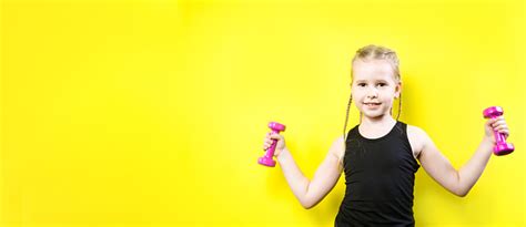 테마 스포츠와 건강 미소와 노란 배경에 포즈 웬과 아름 다운 백인 아이 소녀 분홍색 덤 벨을 들고 있는 작은 운동 선수 광고 배너 텍스트 복사 공간 공간 건강한 생활방식에