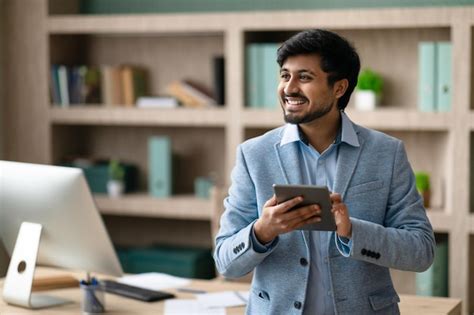 Premium Photo Happy Indian Programmer Man Using Tablet Standing In Modern Office