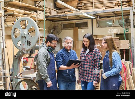Younger And Older Workers Collaborate In A Lumberyard Focusing On Training And Teamwork The