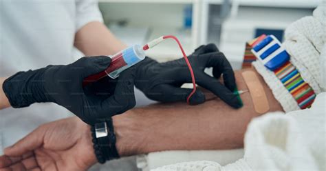 검은 장갑을 끼고 피가 묻은 시험관을 들고 있는 의사의 손을 클로즈업하고 조수가 남자 팔에 바늘을 삽입하는 동안 사진 Unsplash의 피 이미지