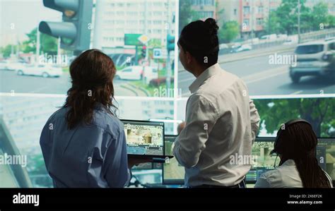 Diverse Team Following City Traffic On A Display In Monitoring Room Reviewing Cctv Satellite