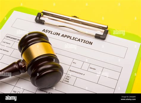 Asylum Concept Showing An Application Form For Asylum On A Yellow Background With A Gavel Stock