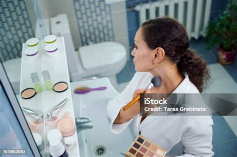 흰색 와플 목욕 가운을 입은 아름다운 여성의 오버 헤드 뷰 욕실 거울 앞에 서있는 메이크업 적용 가정 생활에 대한 스톡 사진 및 기타 이미지 Istock