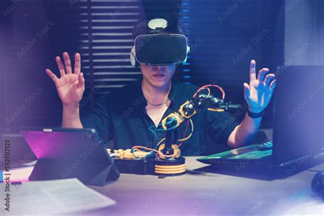 Foto De Young Adult Asian Lesbian Woman With Short Hair Wearing Vr Box For Control Robotic Arm