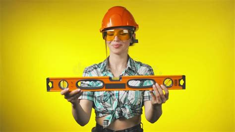 Girl Builder In Orange Safety Helmet Is Holding A Building Level Ruler
