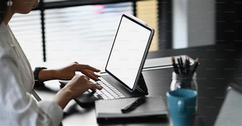 그녀의 작업 공간에서 빈 화면 태블릿에 타이핑하는 젊은 여성의 잘린 샷 사진 Unsplash의 컴퓨터 키보드 이미지