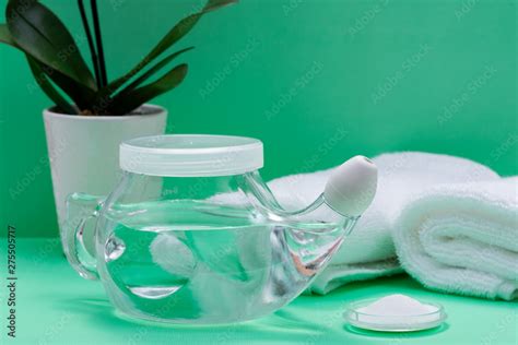 Neti Pot With Soft Comfort Tip Pile Of Saline Purple Orchid Flowers And Rolled Up White Towels