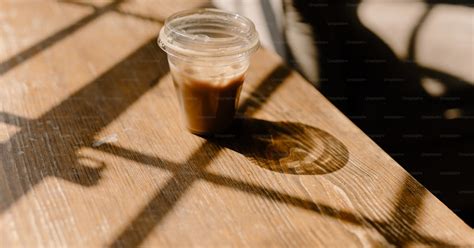 나무 테이블 위에 앉아 있는 커피 한 잔 사진 Unsplash의 플라스틱 컵 이미지