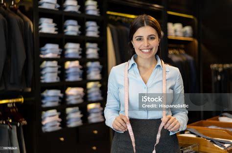 남성 의류 매장의 여성 비즈니스 관리자는 카메라에 미소 그녀의 목 주위에 줄자를 들고 카메라에 미소 테일러드 클로딩에 대한 스톡 사진 및 기타 이미지 Istock