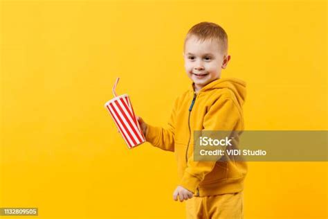 작은 재미 쾌활 한 아이 소년 34 년 늙은 노란 옷을 입고 오렌지 벽 배경에 고립 된 소 다의 컵을 개최 어린이 스튜디오 초상화 사람들 어린 시절 라이프 스타일 개념입니다