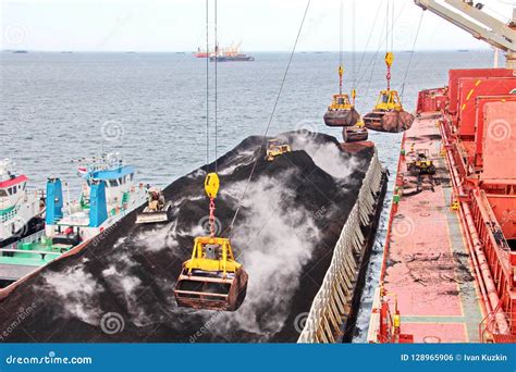 Loading Coal From Cargo Barges Onto A Bulk Carrier Using Ship Cranes And Grabs At The Port Of