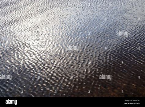 Detailed Close Up View On Water Surfaces With Waves And Ripples And The Sunlight Reflecting At