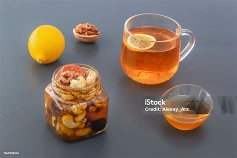 호두 캐슈 건포도 말린 살구 자두와 레몬 회색 테이블에 나무 컵에 차 한 잔 마른 약용 카모마일과 함께 유리 항아리에 꿀을 섞습니다 건강한 식생활에 대한 스톡 사진 및 기타