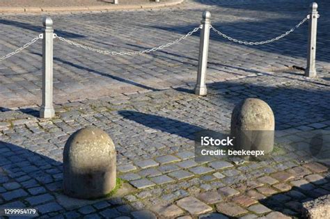 상단에 반구가있는 사각형 모양의 실린더의 돌 장벽 화강암은 주차장에서 정지로 연석 금속 볼라드와 보행자와 차량의 식민지에 대한 체인 장식 울타리 0명에 대한 스톡 사진 및