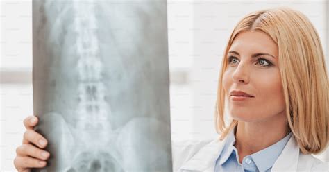 엑스레이를 검사하는 의사 흰색 유니폼을 입은 자신감 넘치는 여의사가 엑스레이 이미지를 들고 그것을 보고 있다 사진 Unsplash의 숙녀 1명만 이미지