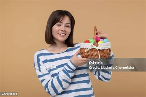 부활절 축하 행사 베이지색 배경에 그려진 달걀로 가득 찬 고리 버들 세공 바구니를 가진 행복한 여자 25 29세에 대한 스톡 사진 및 기타 이미지 Istock