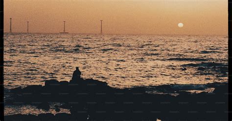 바위에 앉아 석양을 바라보고 있는 사람 사진 Unsplash의 아날로그 이미지